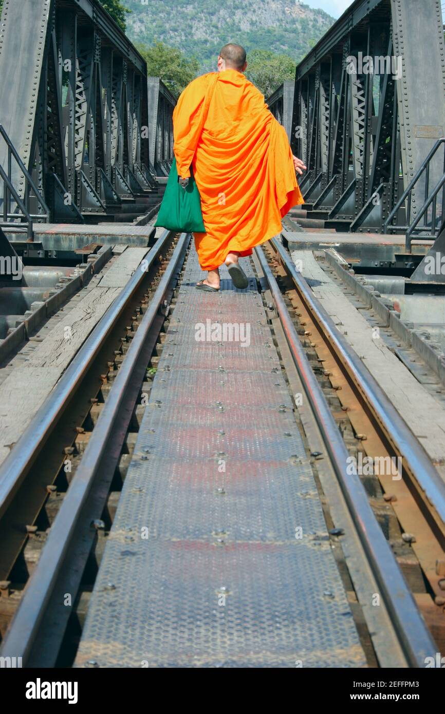 Rear view of a monk walking on a railroad track, Nong Khai, Thailand ...
