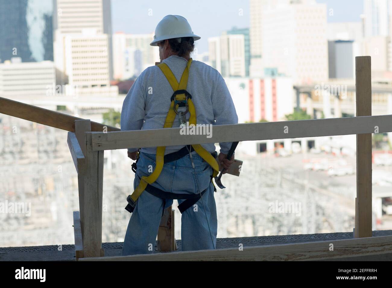 Rear view of a man standing and holding a hammer Stock Photo - Alamy