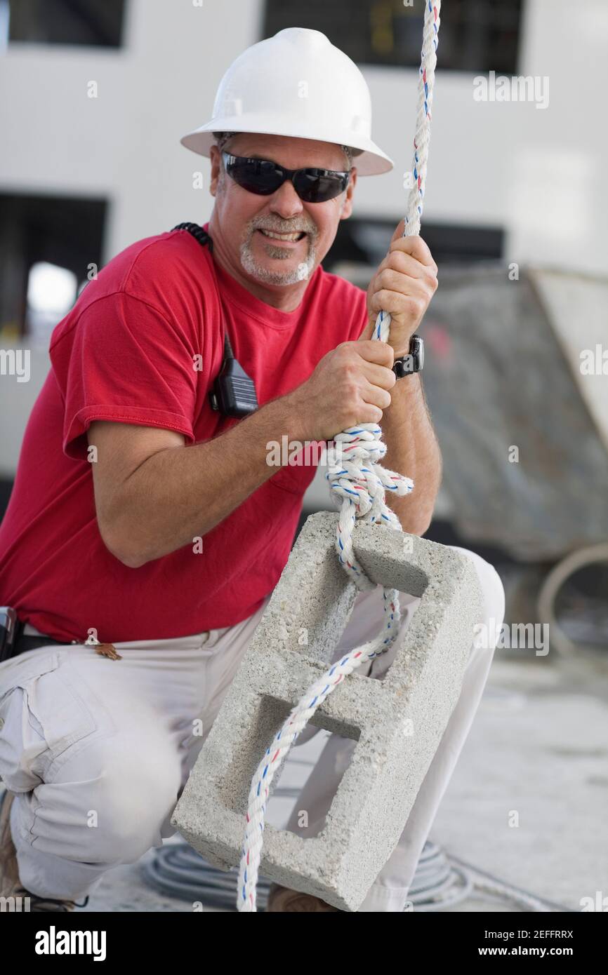 Mature man tightening a rope on a concrete block Stock Photo - Alamy