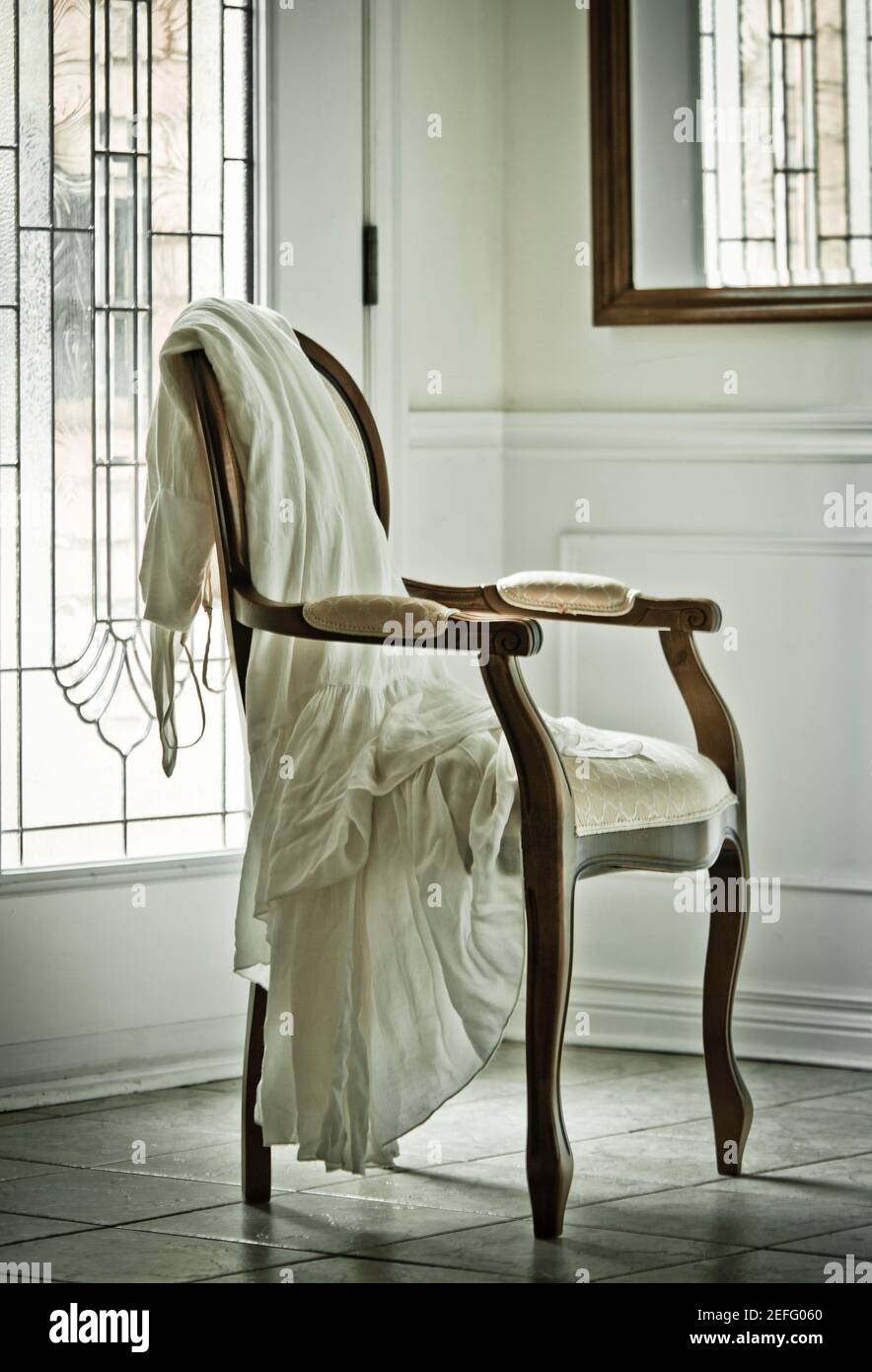 white dress on a chair in an empty room Stock Photo - Alamy