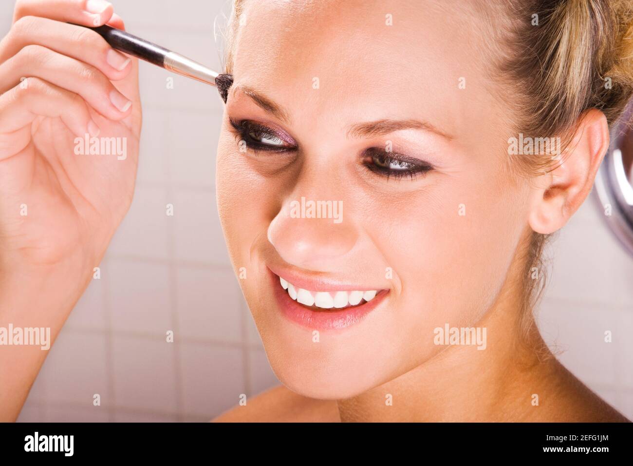 Close-up of a young woman applying eyeshadow Stock Photo - Alamy