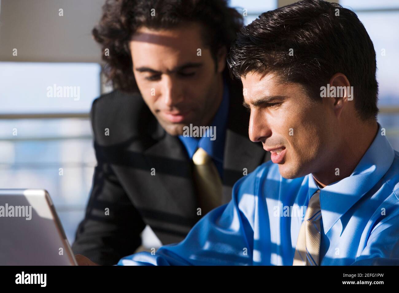 Two businessmen working on a laptop Stock Photo - Alamy