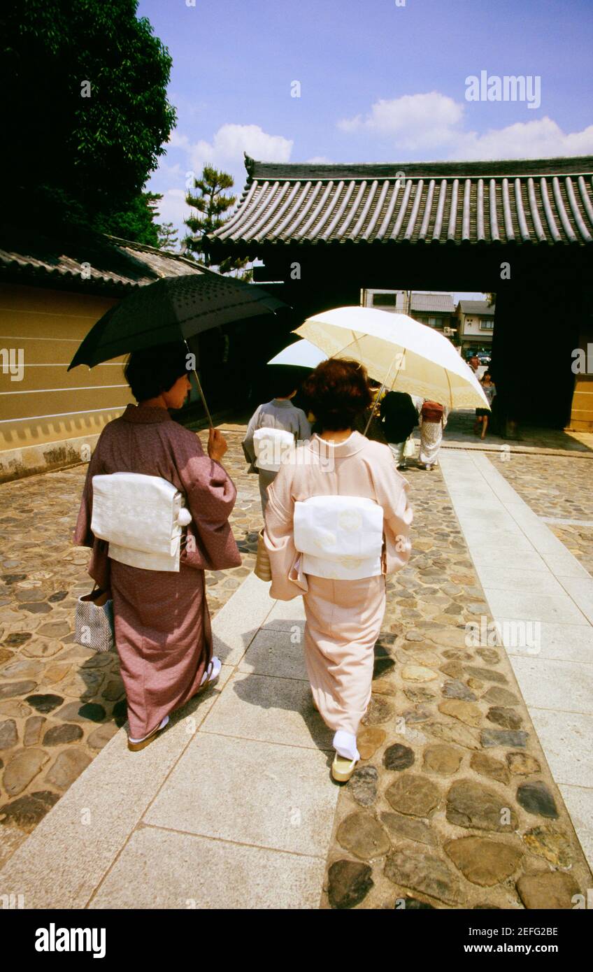 Rear view of two mid adult women walking on a walkway, Daitokuji Temple ...