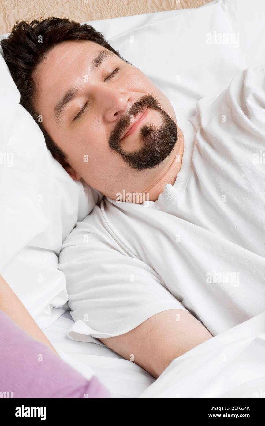 Mid adult man sleeping on the bed Stock Photo - Alamy
