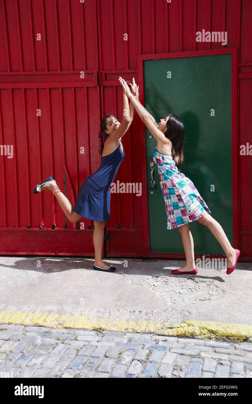 Side profile of two young women giving high- five to each other Stock ...