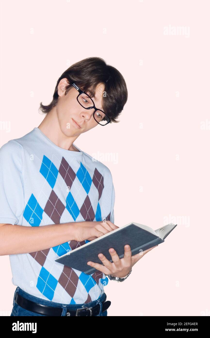 Teenage boy standing and reading a book Stock Photo - Alamy