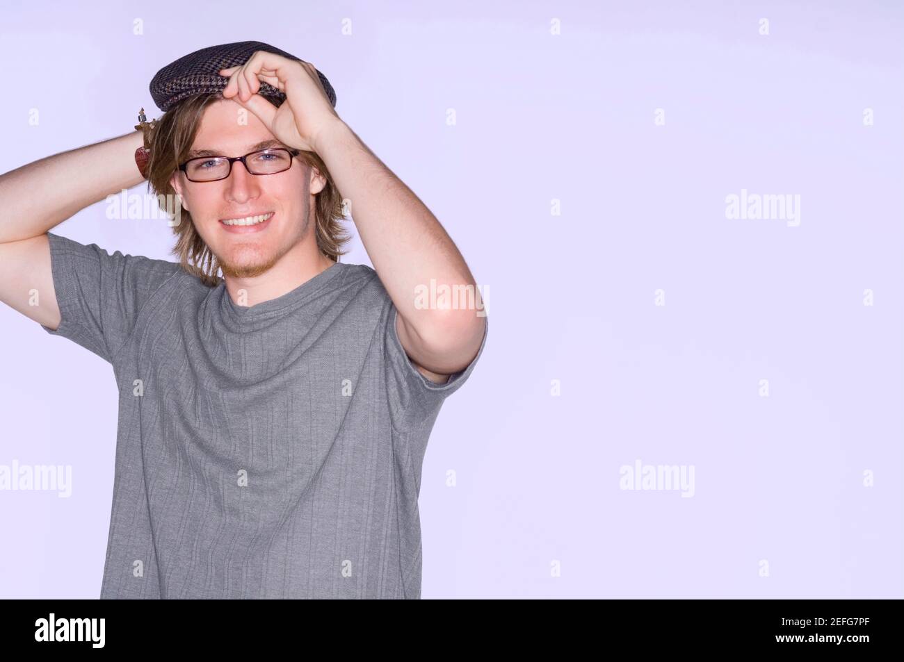 Portrait of a young man adjusting his flat cap and smiling Stock Photo ...