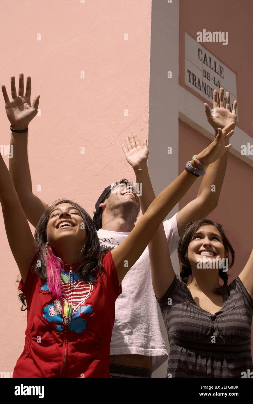 Two young women and a young man standing together with their arms ...