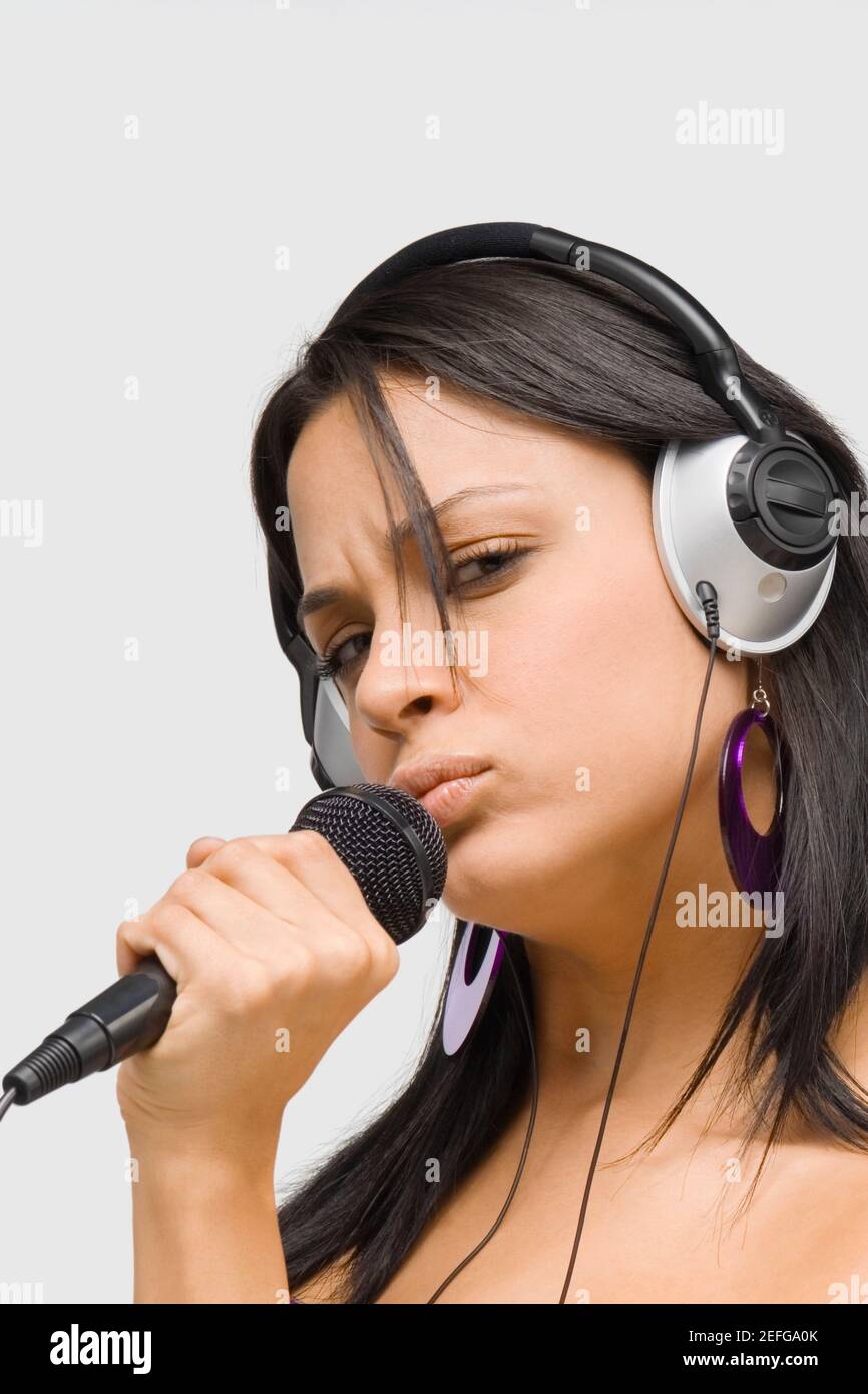 Portrait of a young woman singing into a microphone Stock Photo - Alamy