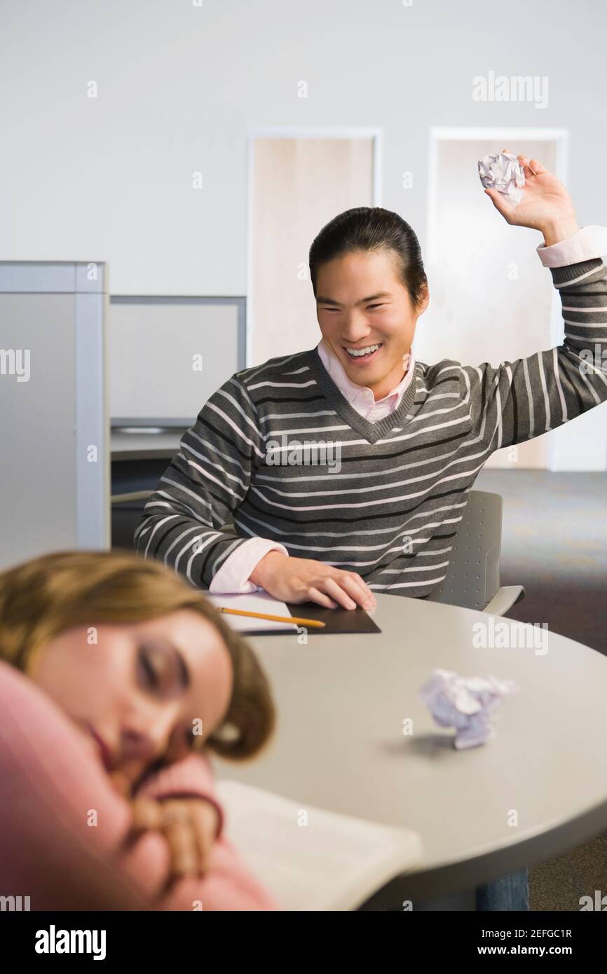Close up of a young woman napping and a young man throwing a crumpled ...