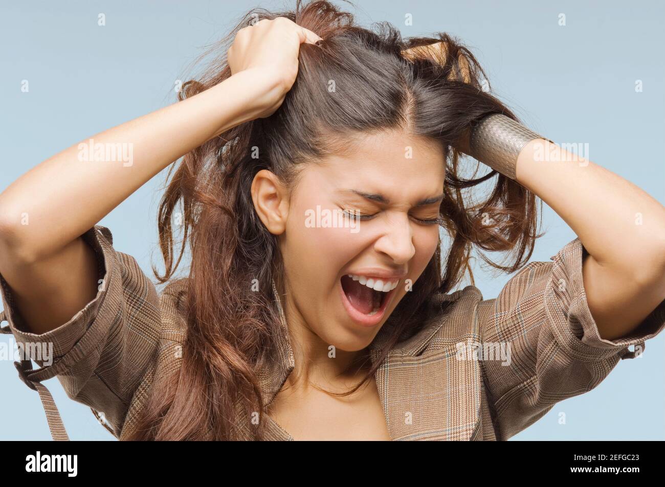 Close-up of a young woman screaming with her hands in her hair Stock ...
