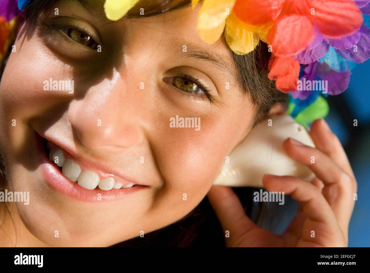Portrait of a girl wearing flowers and listening to a conch shell Stock ...