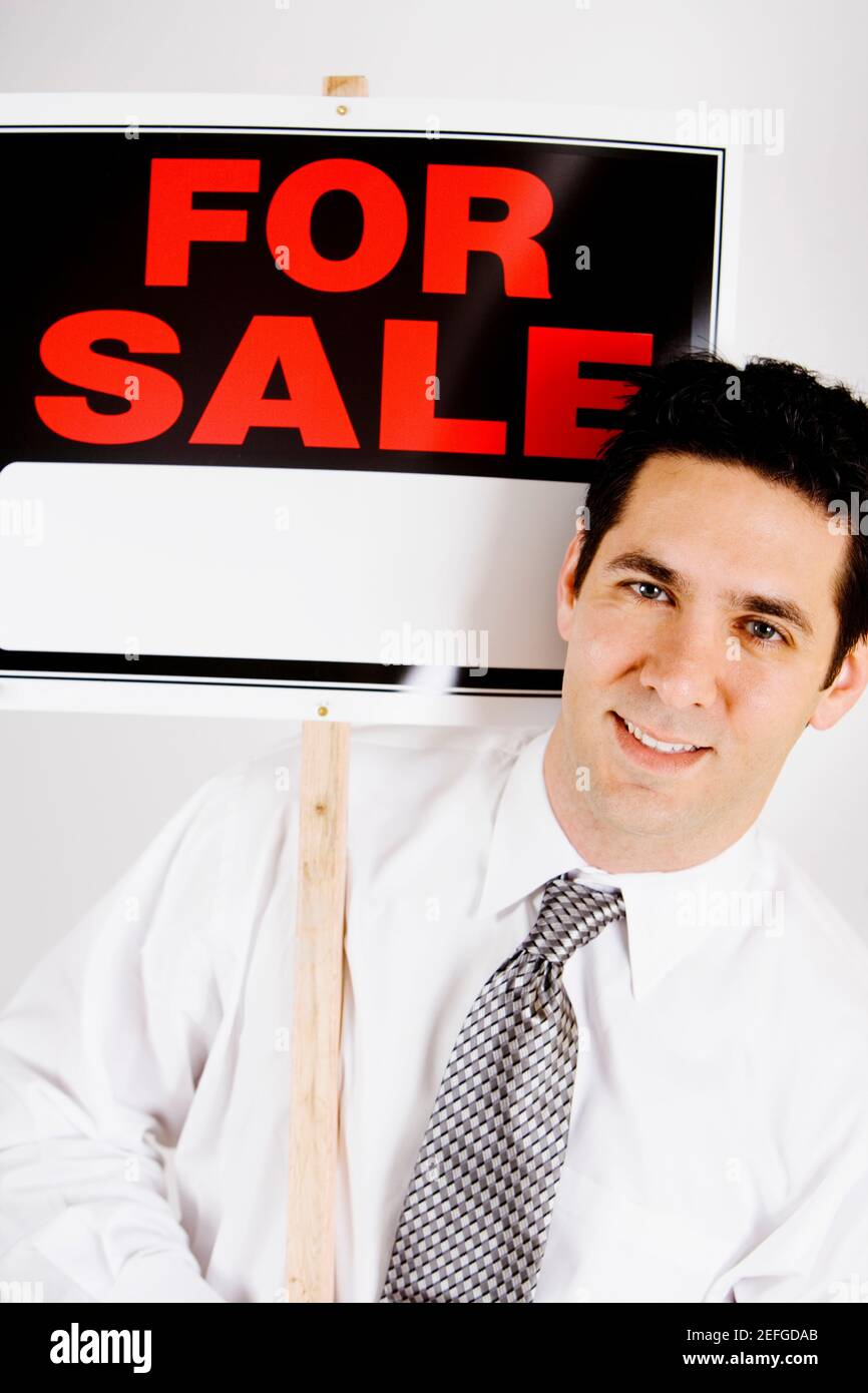 Portrait of a businessman holding For Sale sign board Stock Photo - Alamy