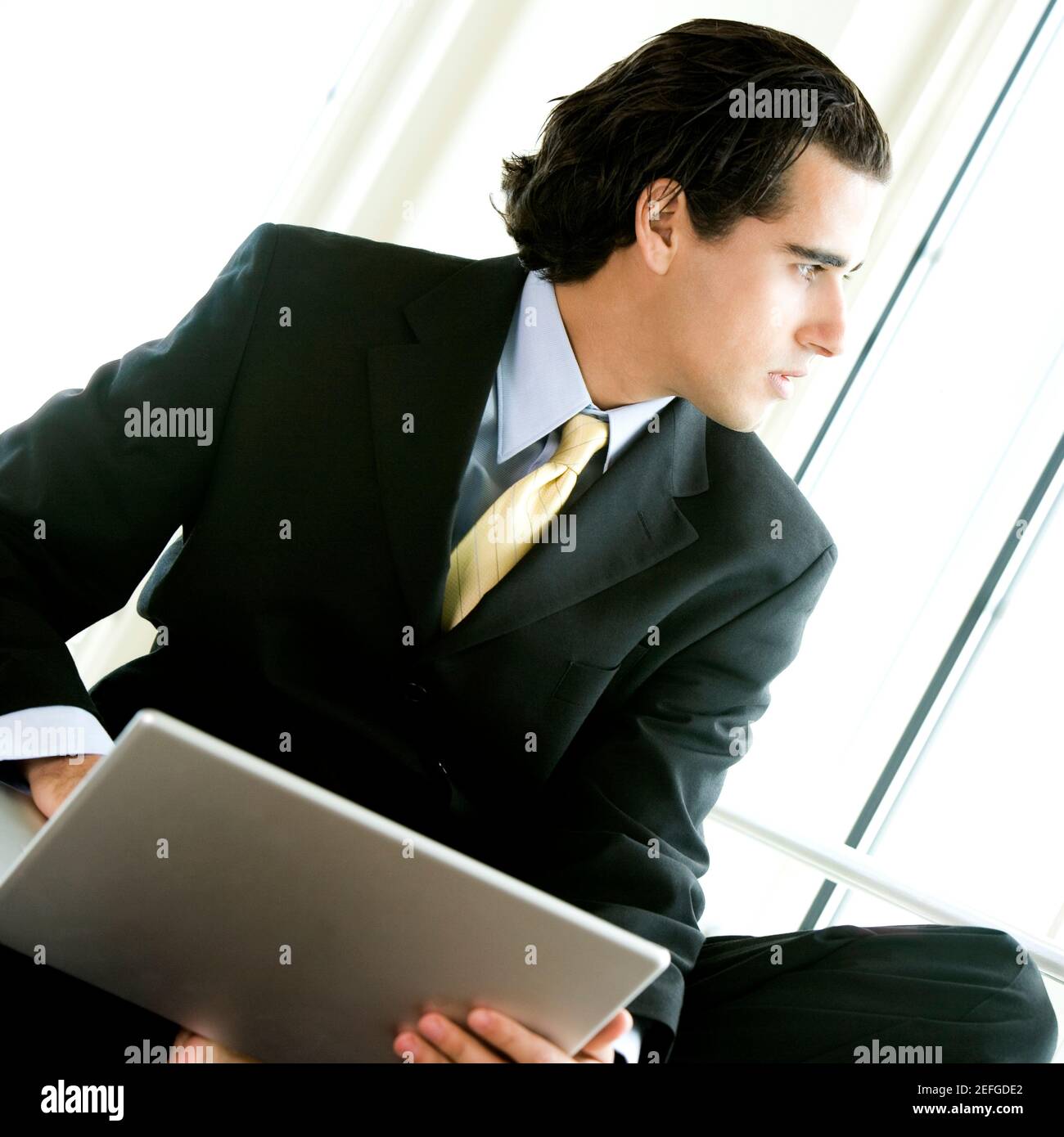 Young businessman with laptop looking sideways hi-res stock photography ...
