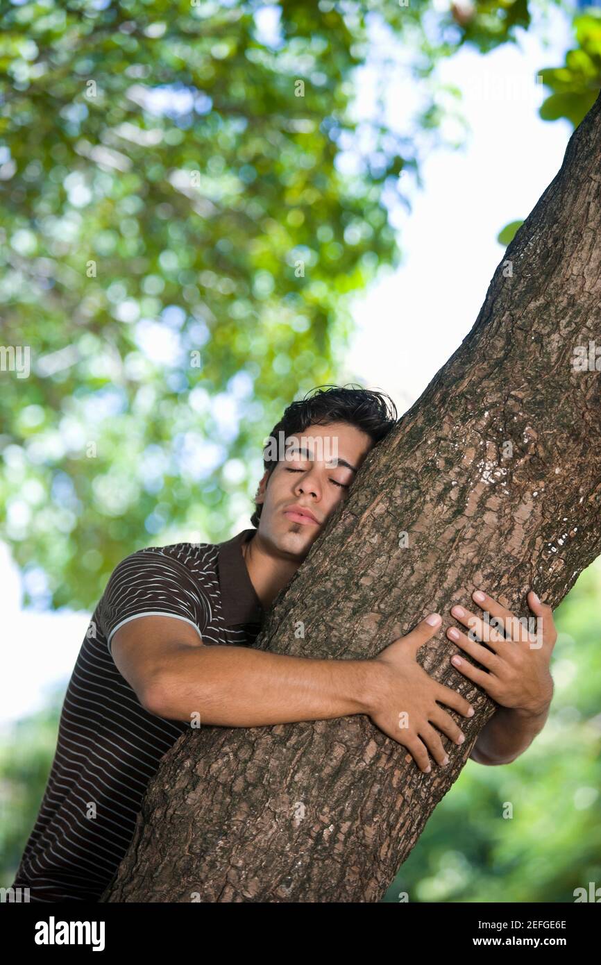 Young man hugging tree trunk hi-res stock photography and images - Alamy