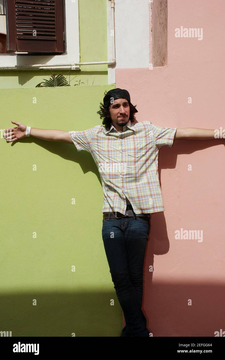 Young man leaning against a wall with his arms outstretched Stock Photo ...