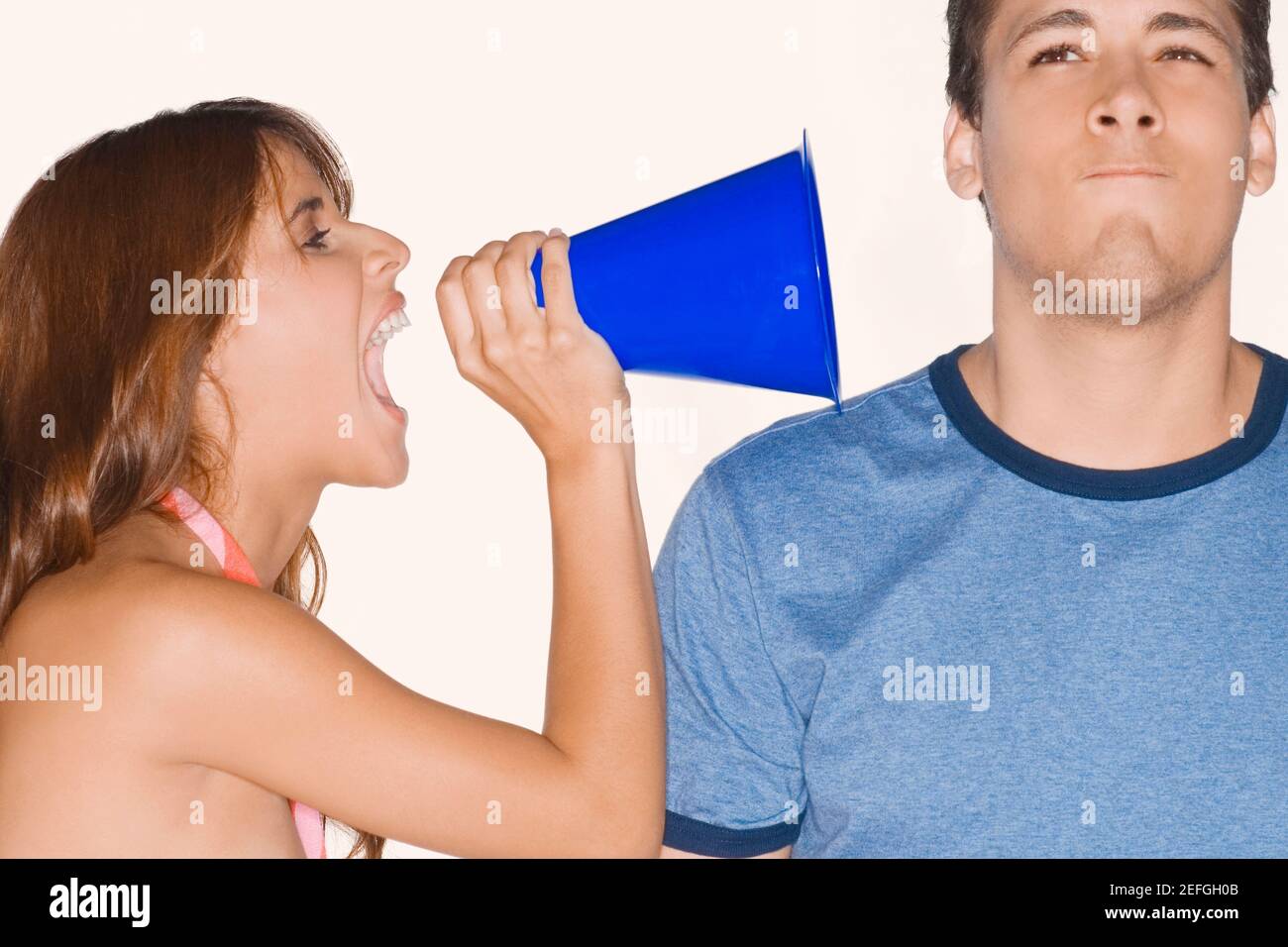 Side profile of a young woman shouting with a megaphone into a young ...