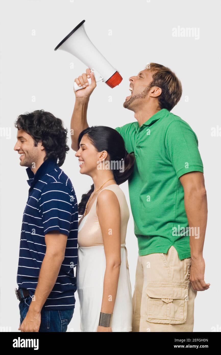 Side profile of a mid adult man shouting into a megaphone behind his ...