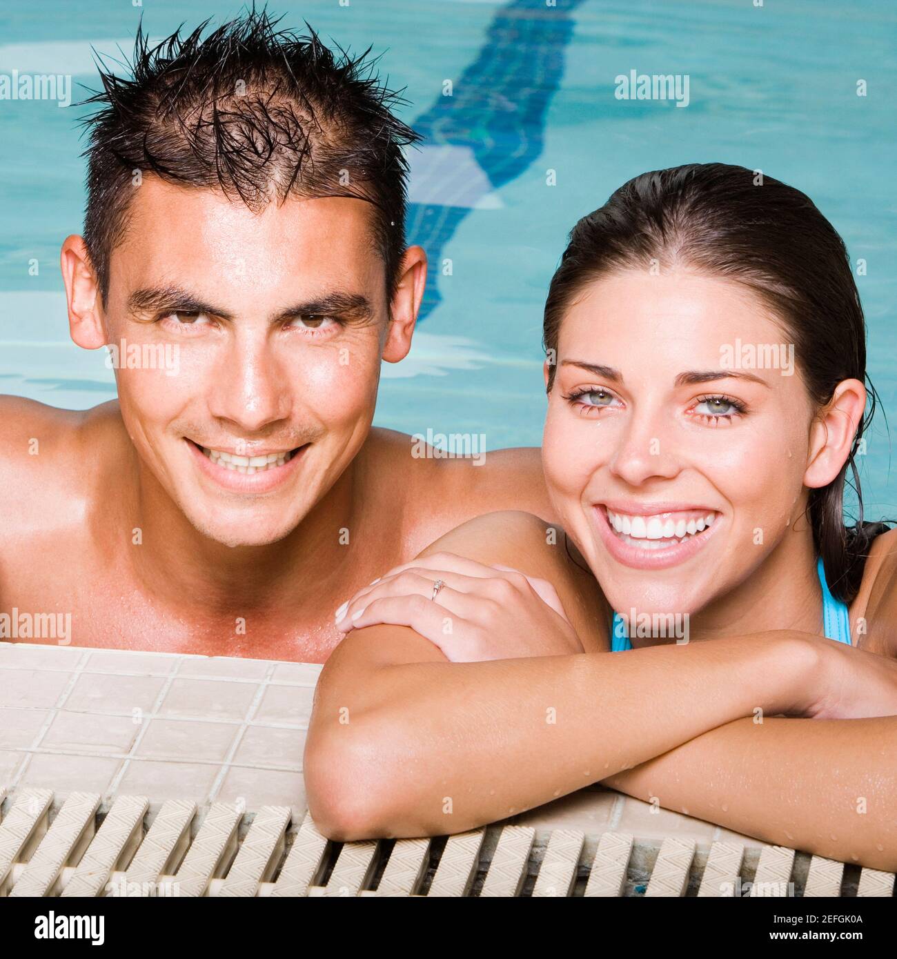Portrait of a young couple leaning at the edge of a swimming pool Stock ...