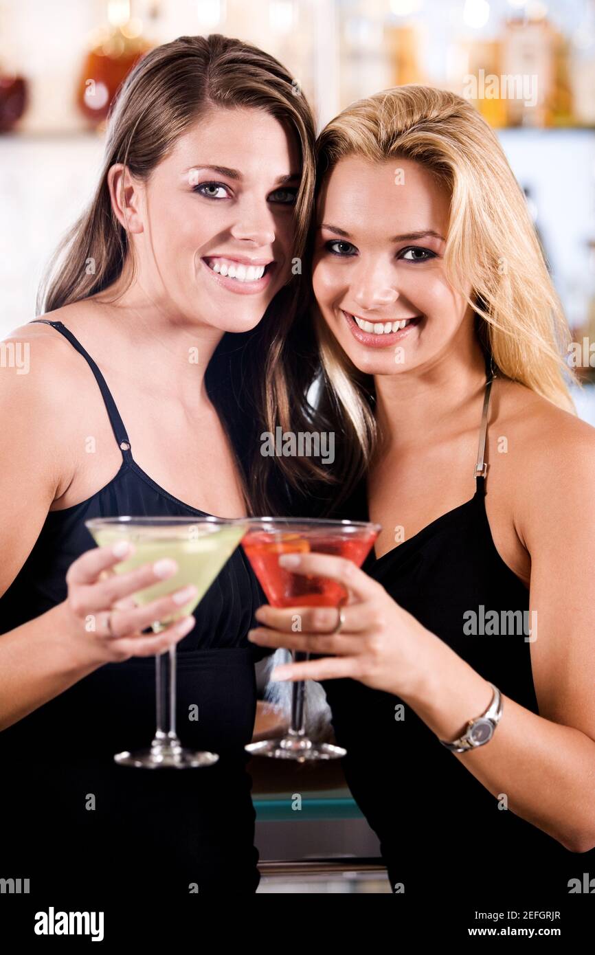 Portrait of two young women toasting martinis in a bar Stock Photo - Alamy