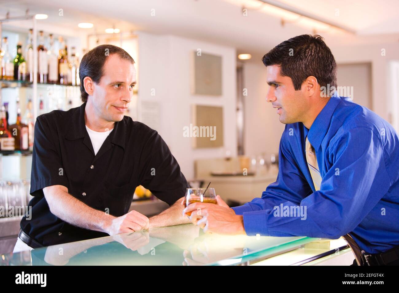 Side profile of a businessman and a bartender at a bar counter Stock ...
