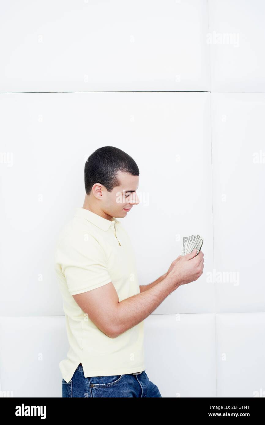 Side profile of a young man counting dollar bills Stock Photo - Alamy