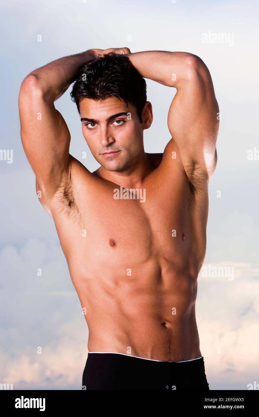 Portrait of a young man standing with his hands behind his head Stock ...