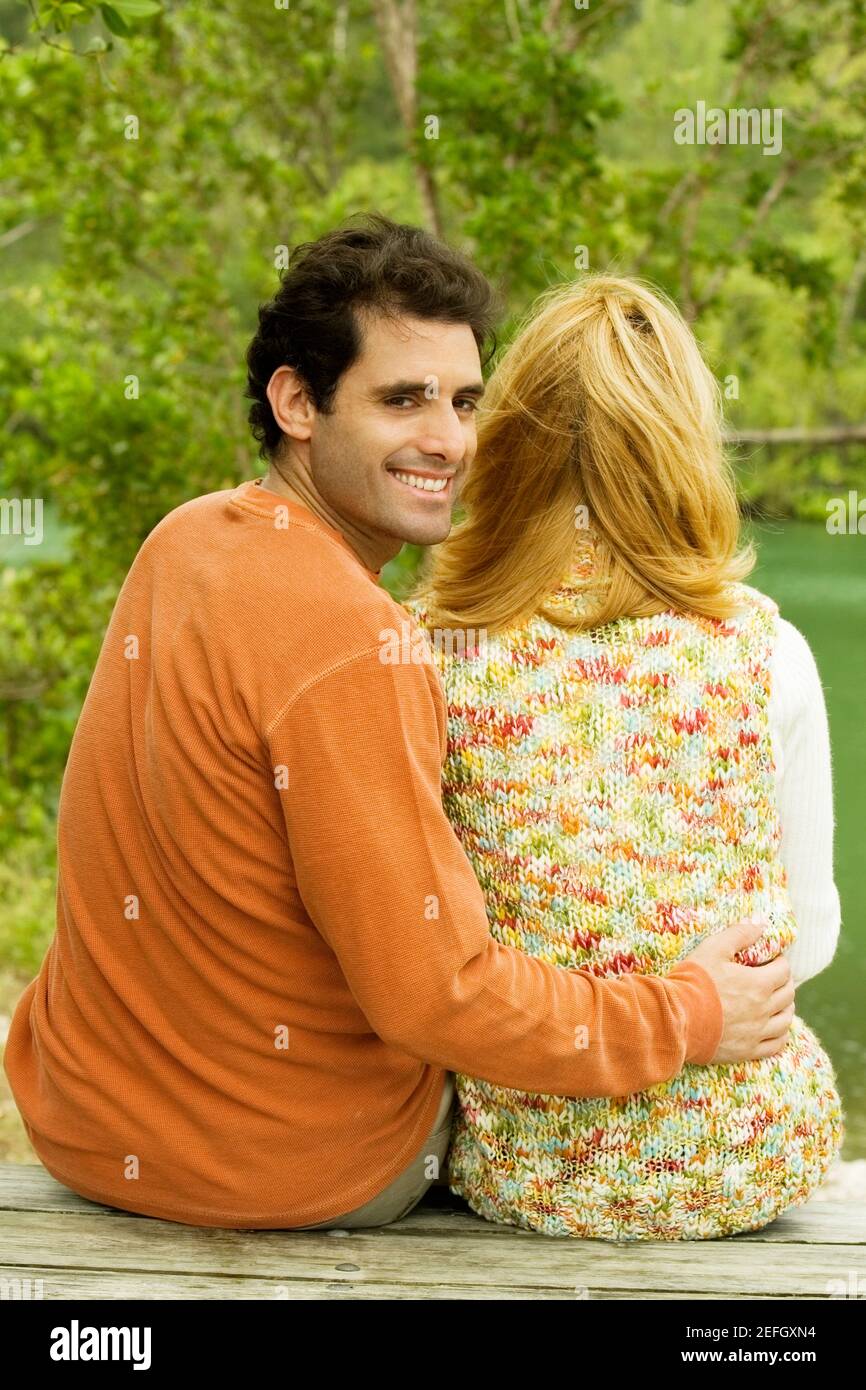 Rear view of a mid adult man sitting with his arm around a young woman ...