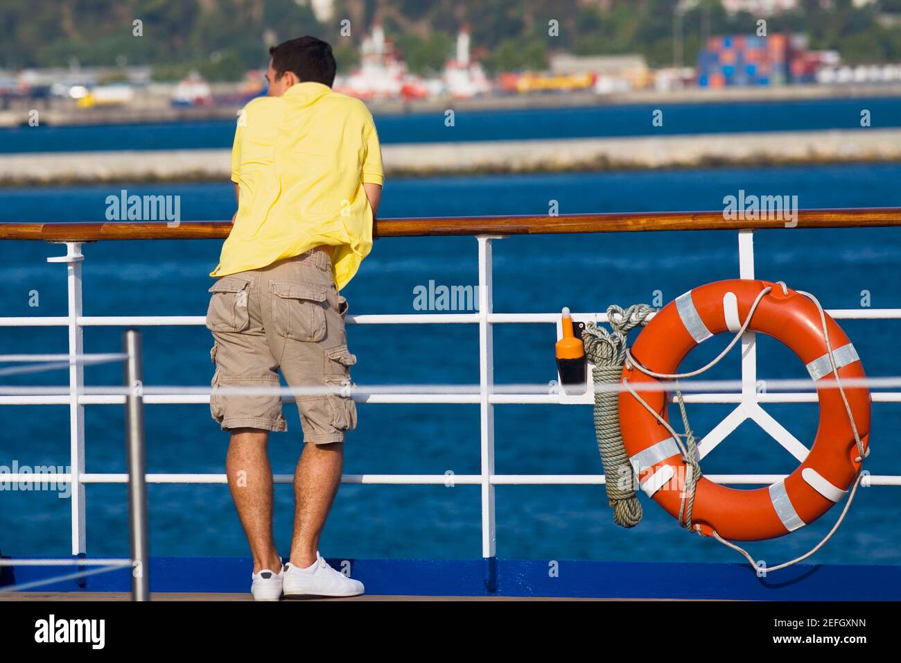 Rear view of a man leaning against a railing Stock Photo - Alamy