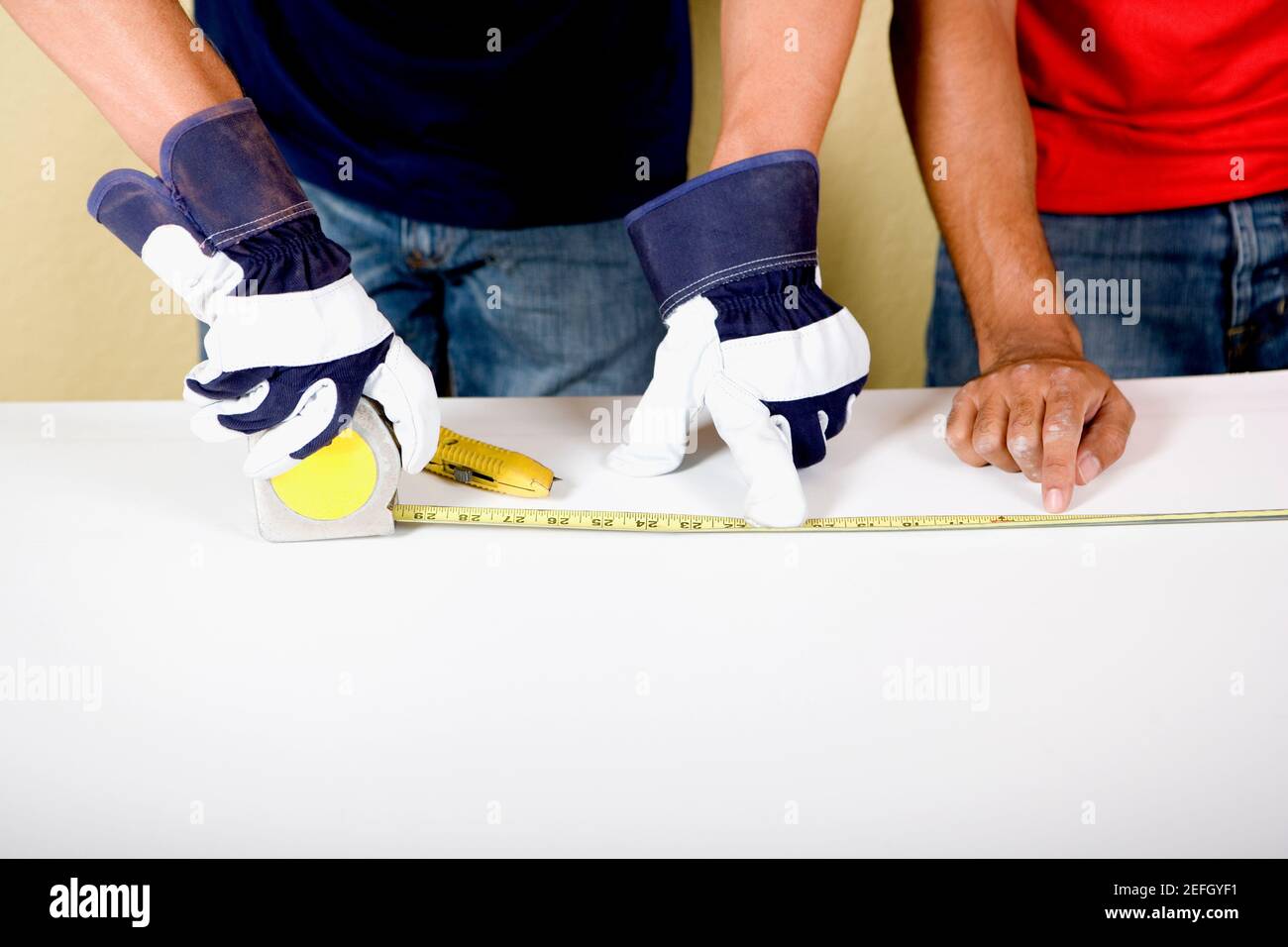 Mid section view of two men measuring with a measuring tape Stock Photo ...
