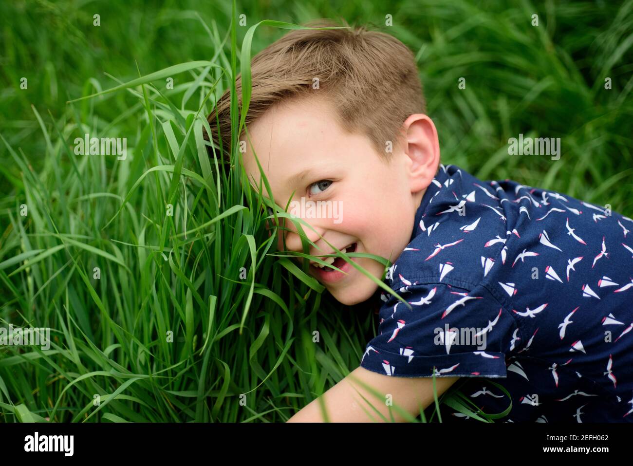 Smiling child boy with grass background. Cute kid enjoying on field ...