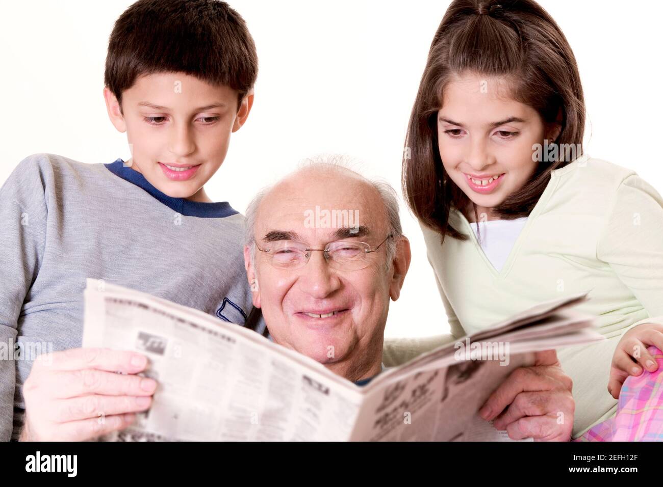 Grandfather reading a newspaper with his grandson and his granddaughter ...
