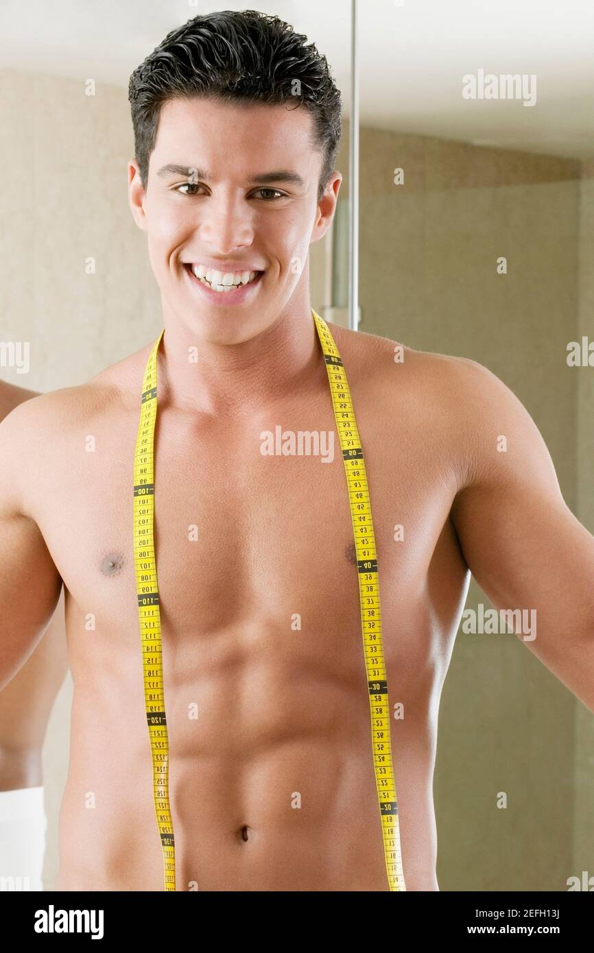 Portrait of a young man standing with a tape measure around his neck ...