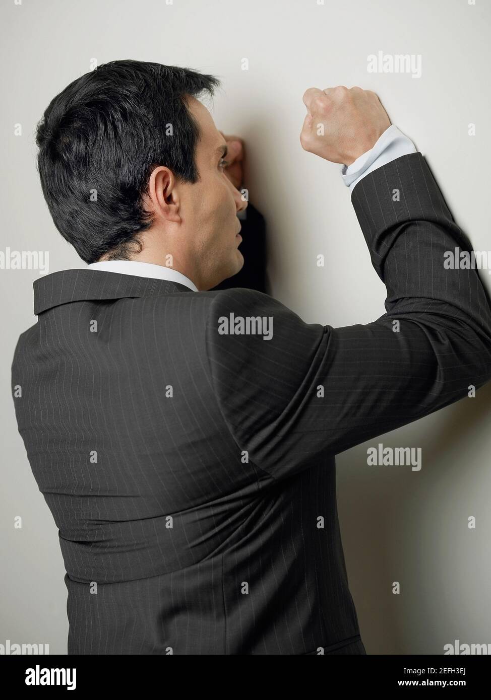 Rear view of a businessman hitting a wall Stock Photo - Alamy
