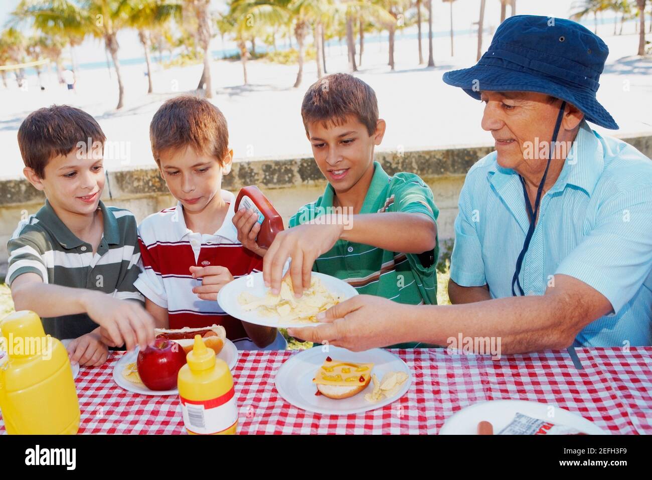Senior man giving potato chips to his grandsons Stock Photo - Alamy