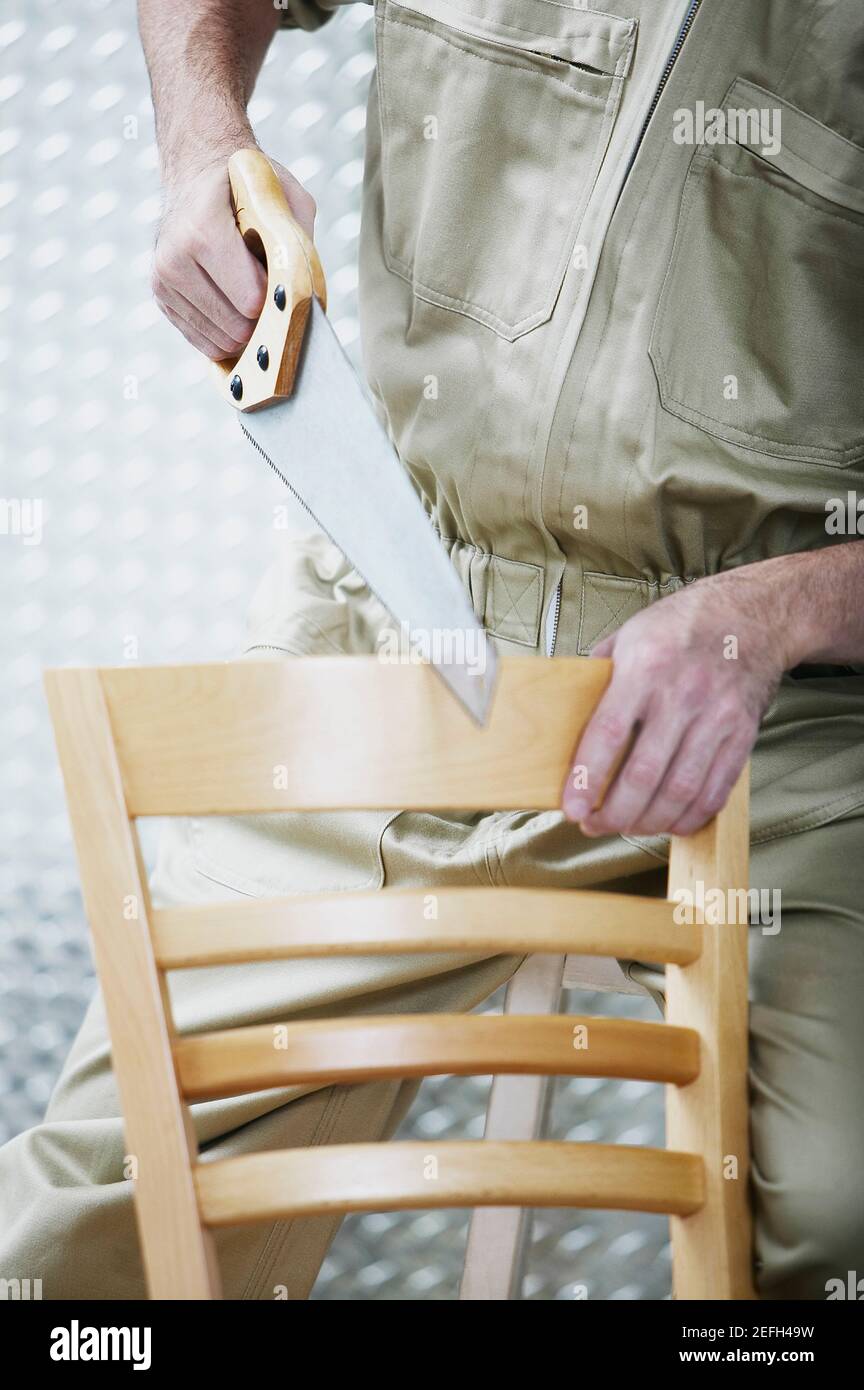 Mid section view of a man sawing a chair Stock Photo - Alamy