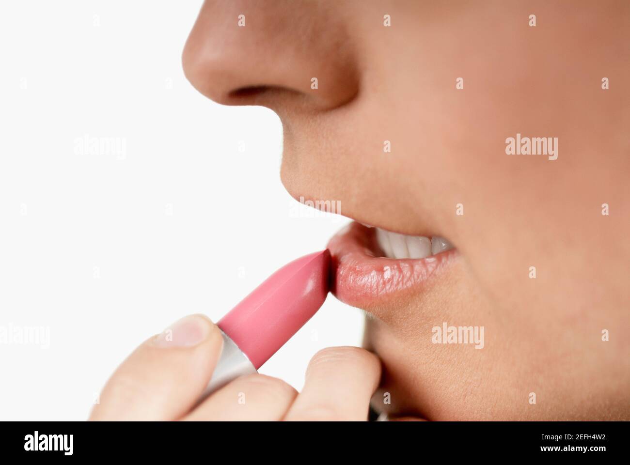 Profile of young woman applying lipstick hi-res stock photography and ...