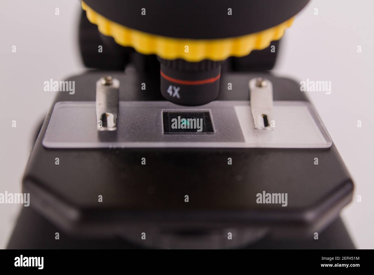 a glass for analysis under a microscope with a sample on a white ...