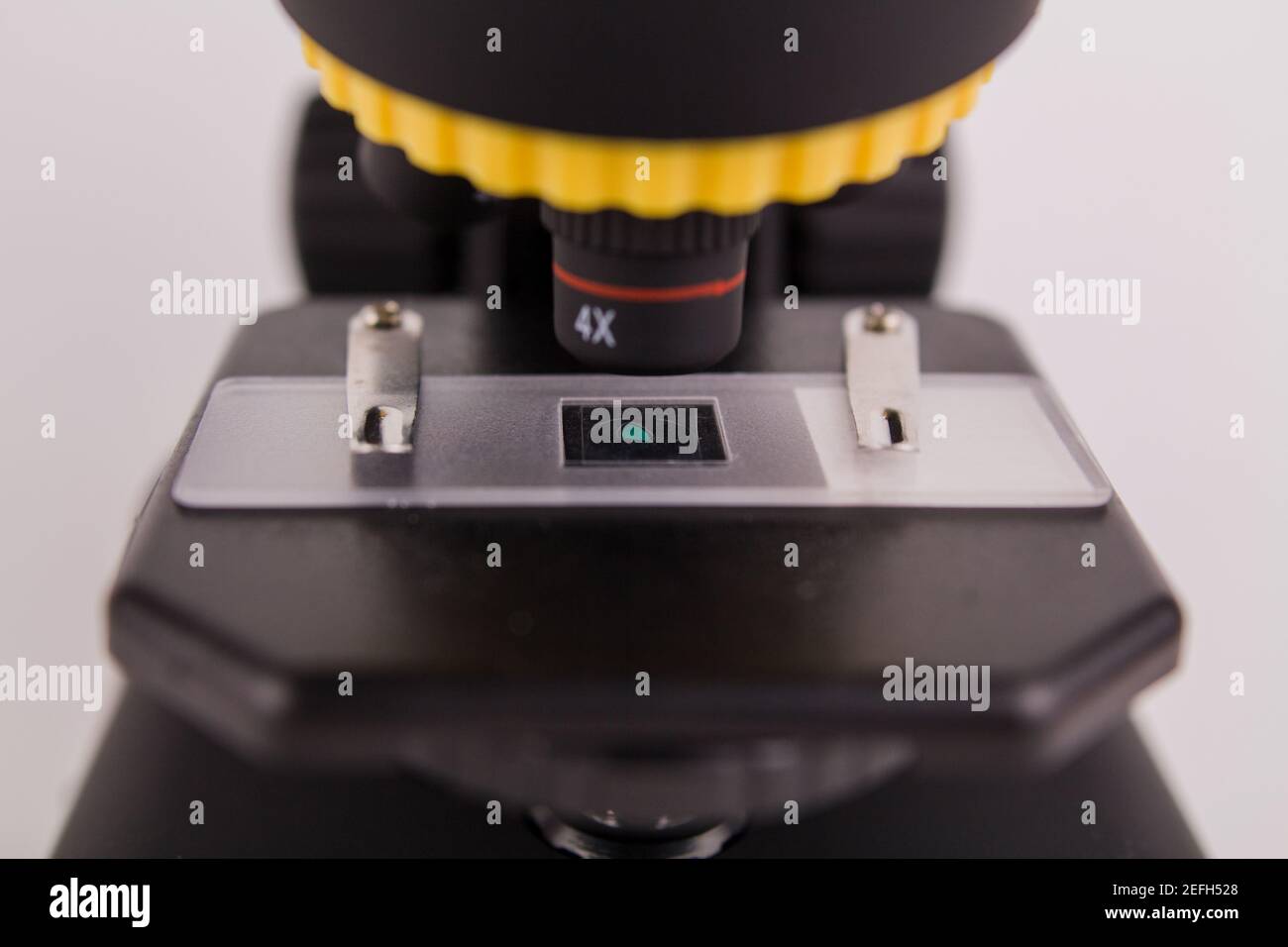 a glass for analysis under a microscope with a sample on a white ...