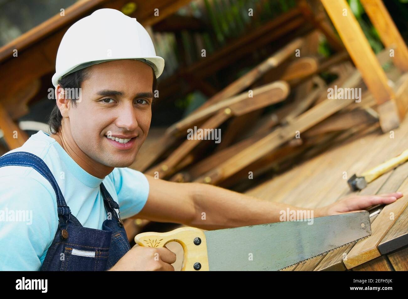 Portrait of a carpenter cutting a plank with a saw Stock Photo - Alamy