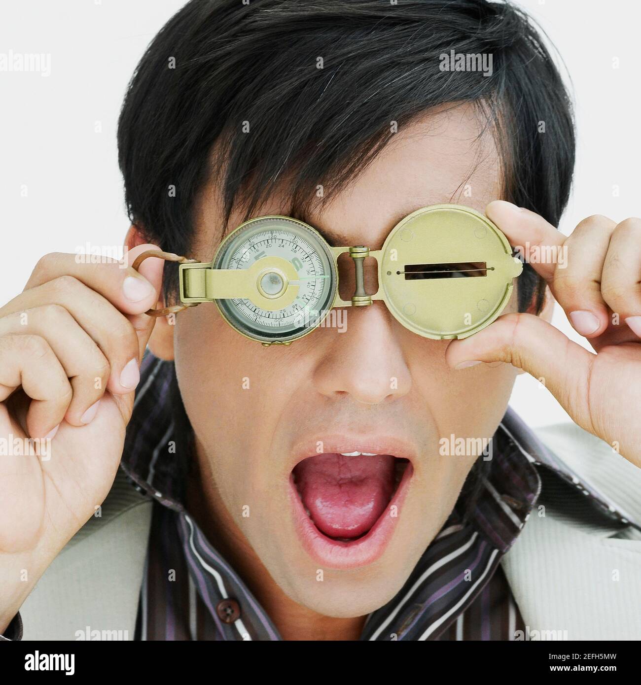 Close up of a young man looking through a compass Stock Photo - Alamy