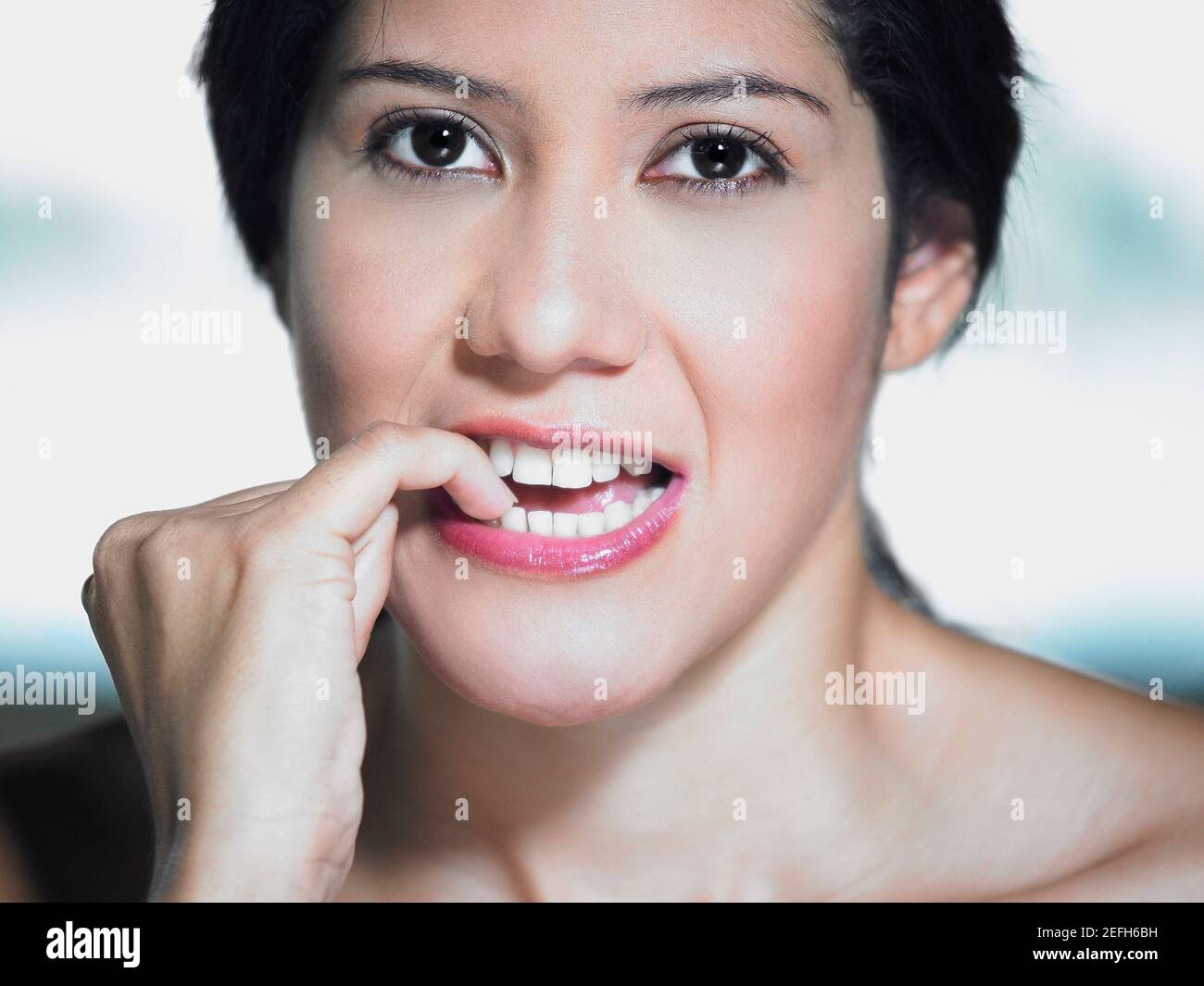 Portrait of a young woman biting her nails Stock Photo - Alamy