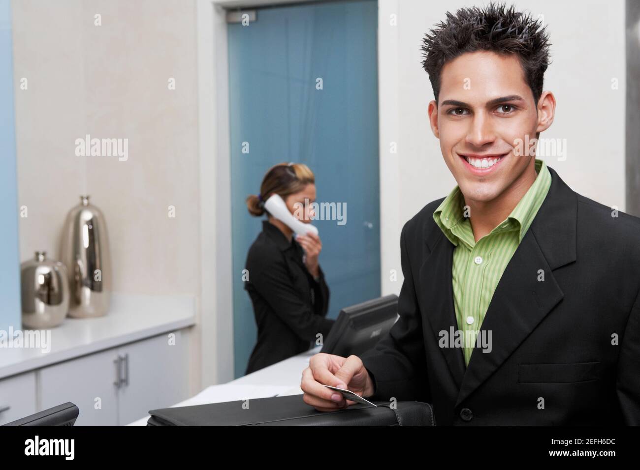 Portrait of a businessman standing at a hotel reception with a ...