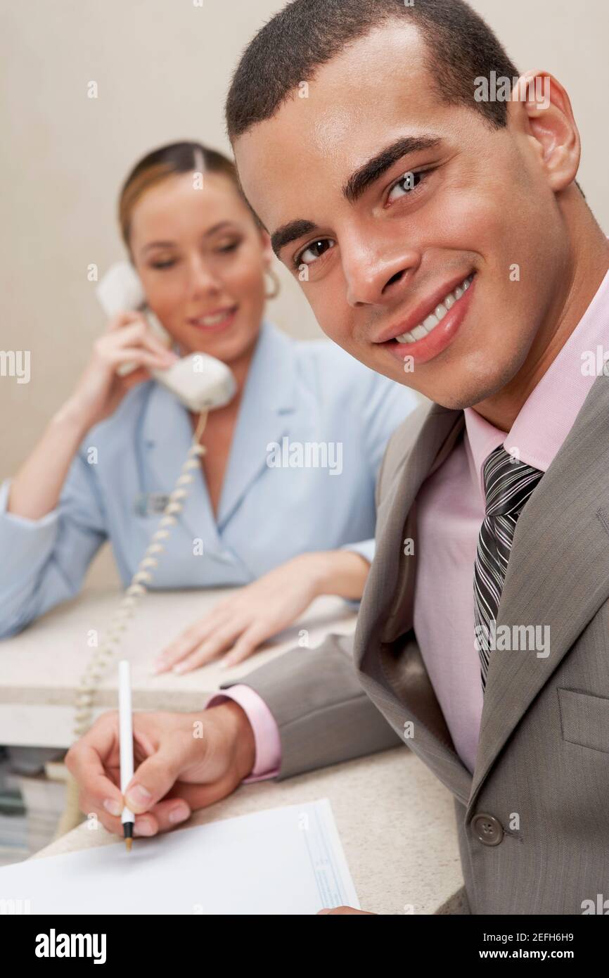 Hotel receptionist talking to businessman and woman hi-res stock ...