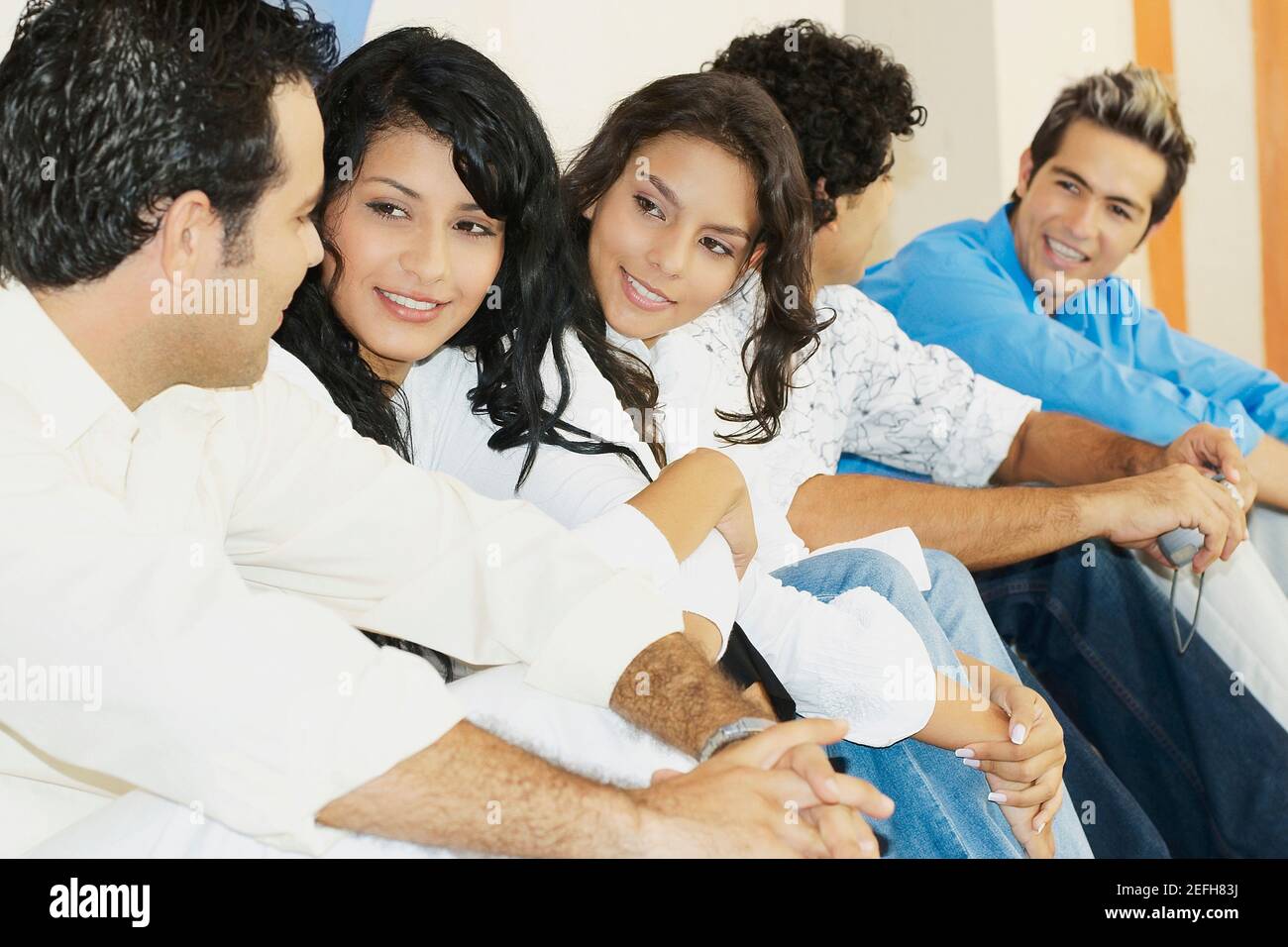 Five friends sitting together and smiling Stock Photo - Alamy