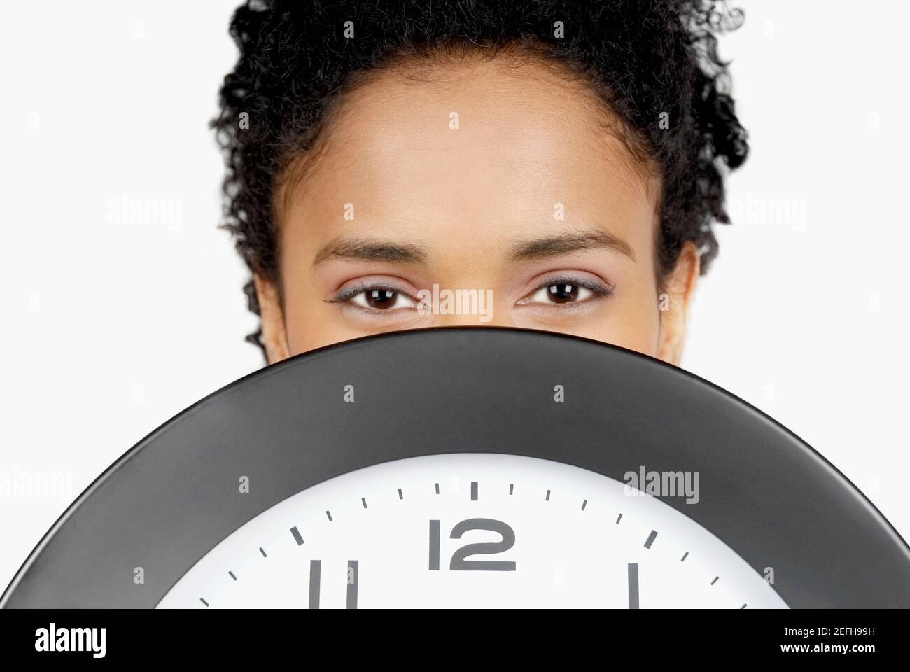 Portrait of a businesswoman hiding her face behind a clock Stock Photo ...
