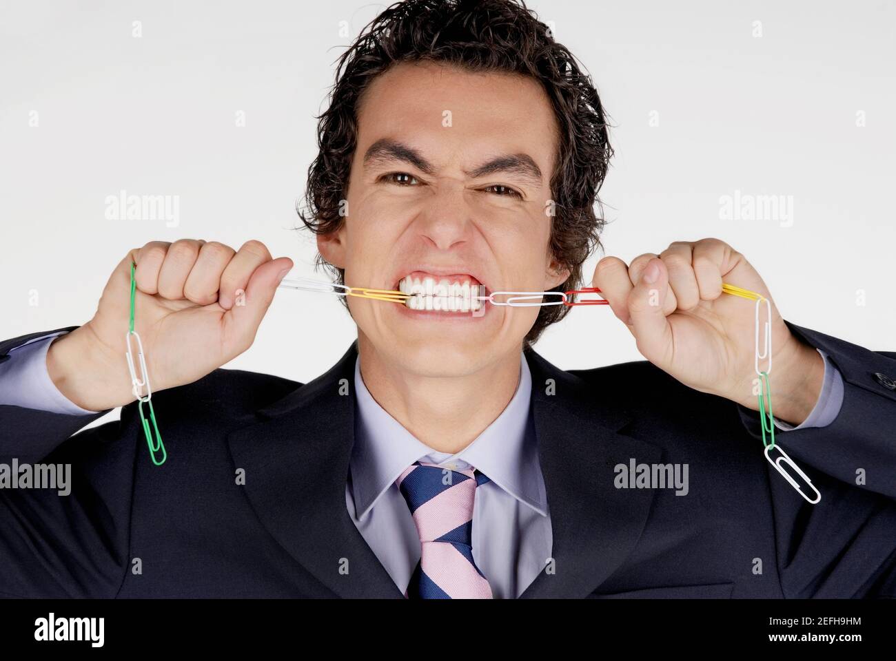 Portrait of a businessman biting a chain of paper clips Stock Photo - Alamy