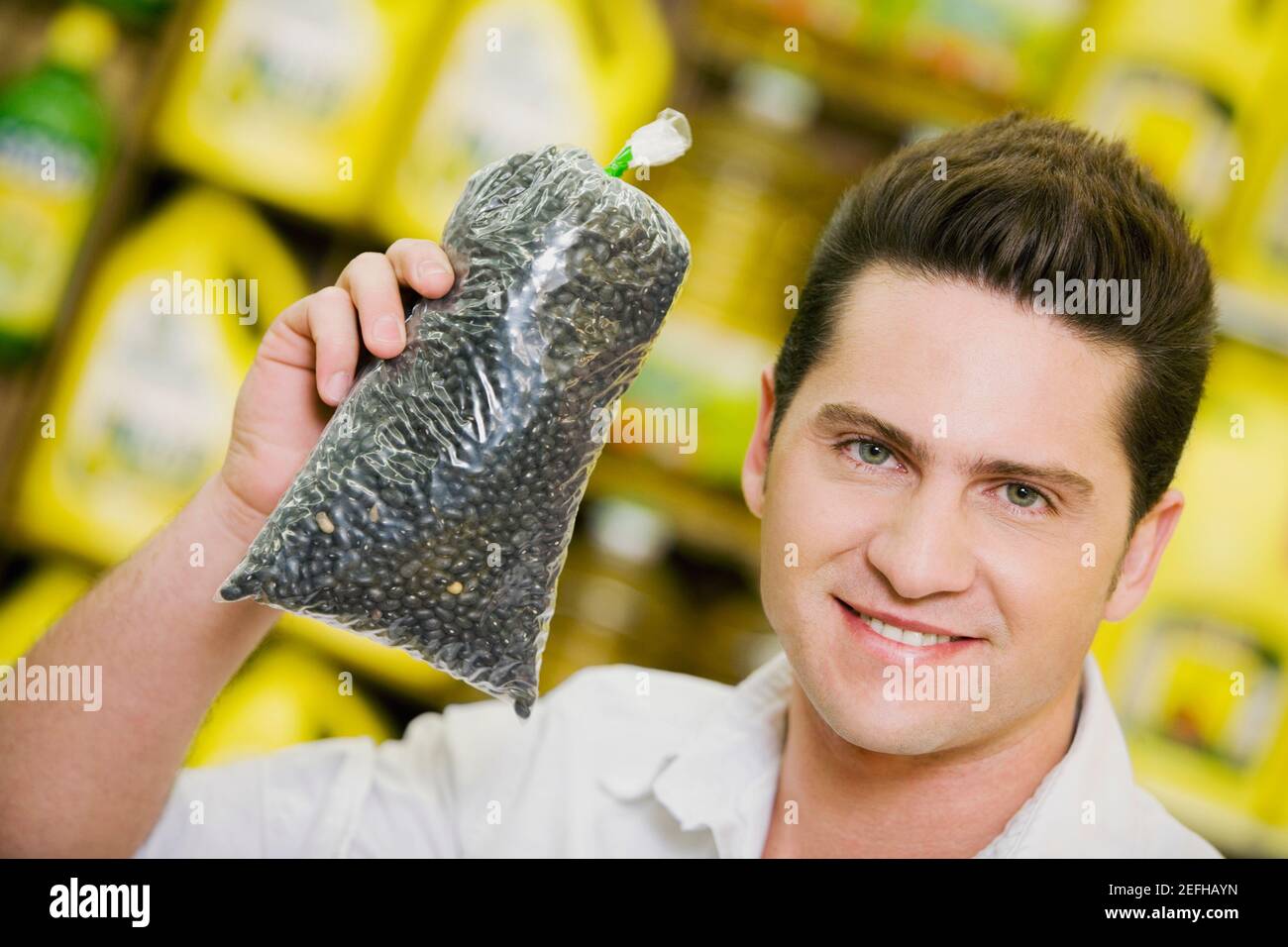 Portrait of a young man holding a packet of pulses Stock Photo - Alamy