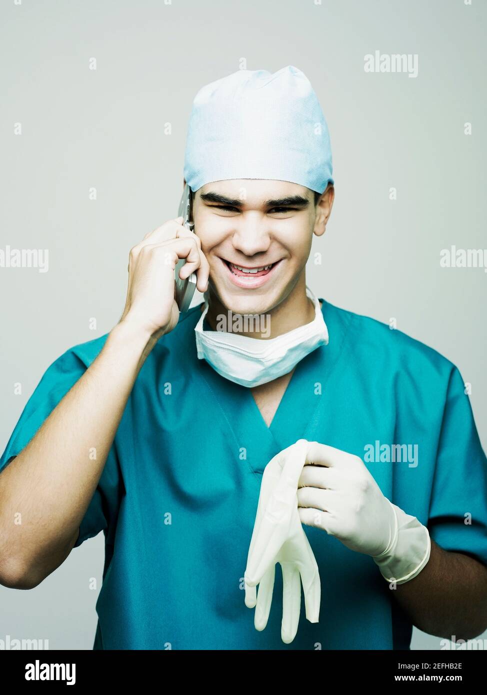 Portrait of a male surgeon smiling and using a mobile phone Stock Photo ...