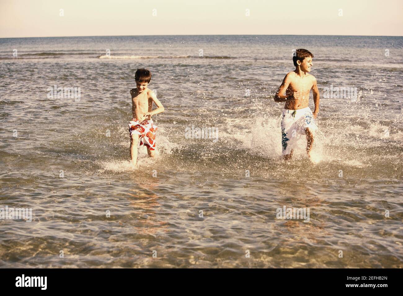 Teenage boy running in water with his brother Stock Photo - Alamy
